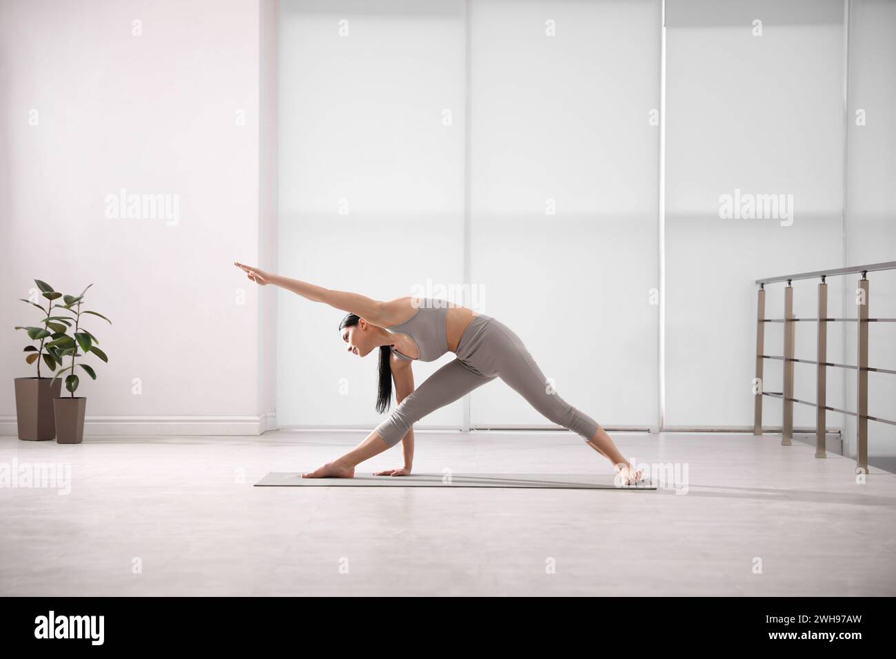 Young woman practicing triangle asana in yoga studio. Utthita ...