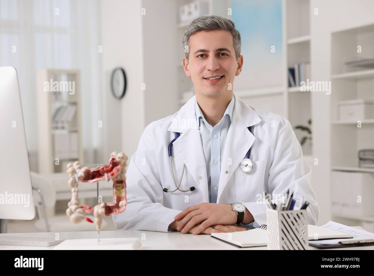 Gastroenterologist with anatomical model of large intestine at table in ...