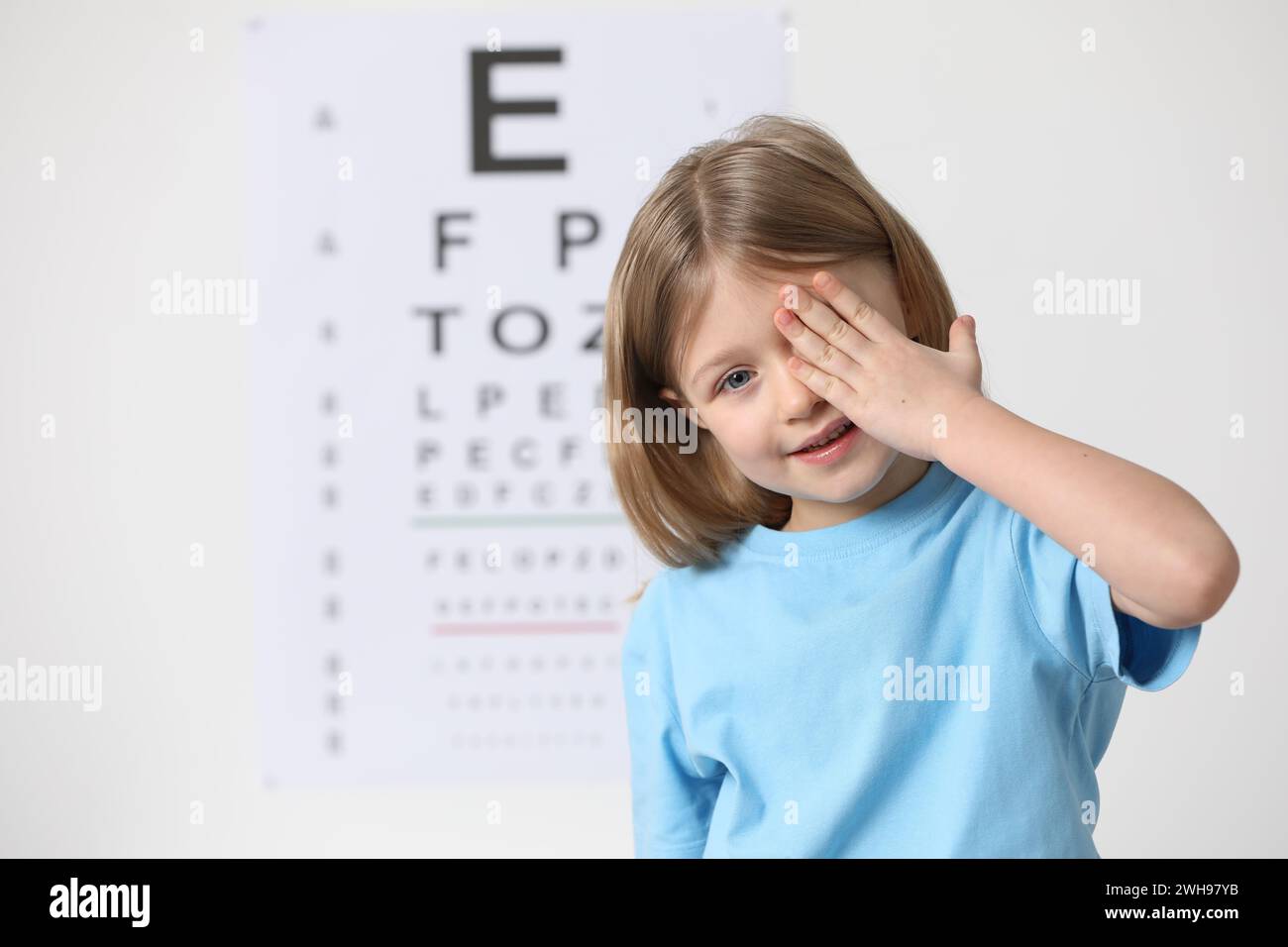 Little girl covering her eye against vision test chart Stock Photo - Alamy