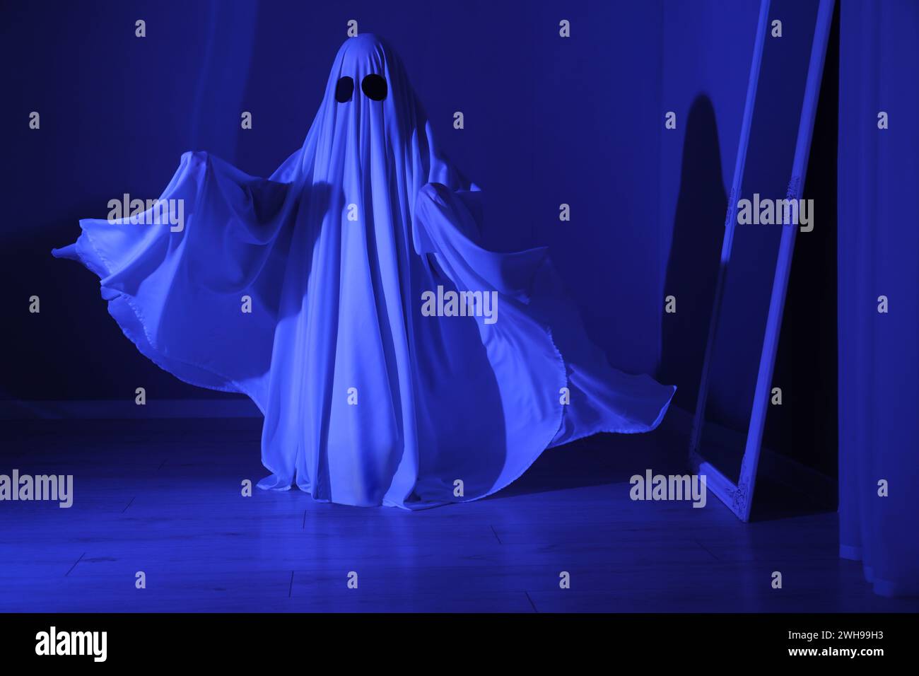 Creepy ghost. Woman covered with sheet in blue light Stock Photo - Alamy