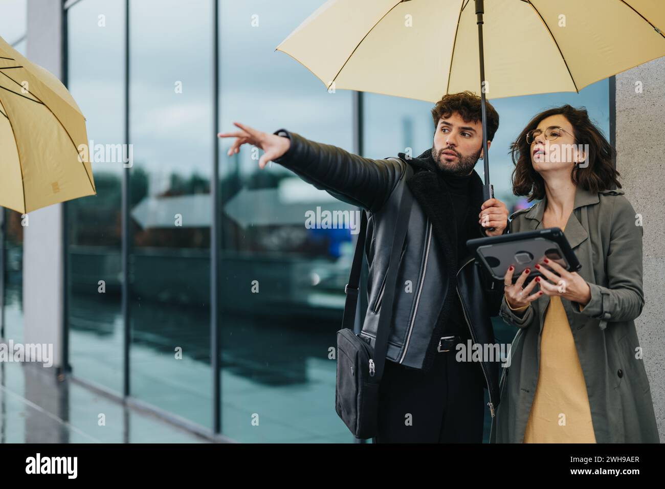 Two business executives in smart casual wear holding yellow umbrellas ...