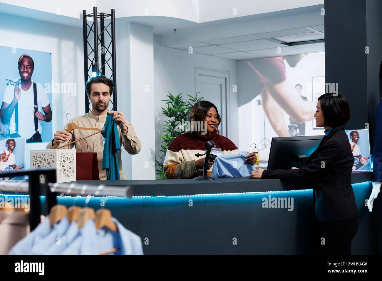 Clothing store diverse cashiers scanning garments at checkout and ...