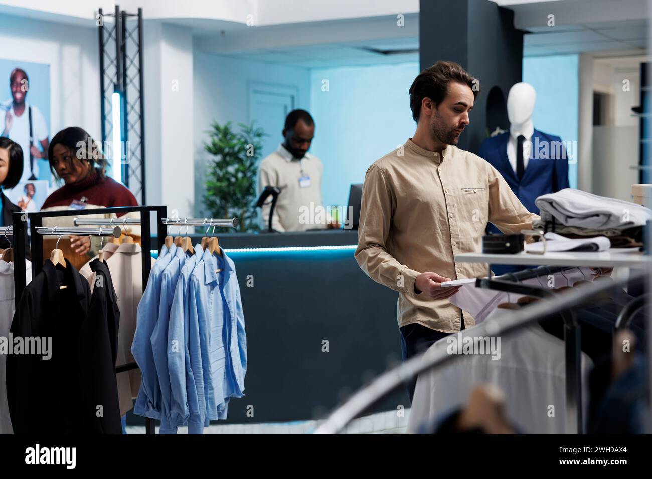 Caucasian man browsing through rack of clothing items at store ...