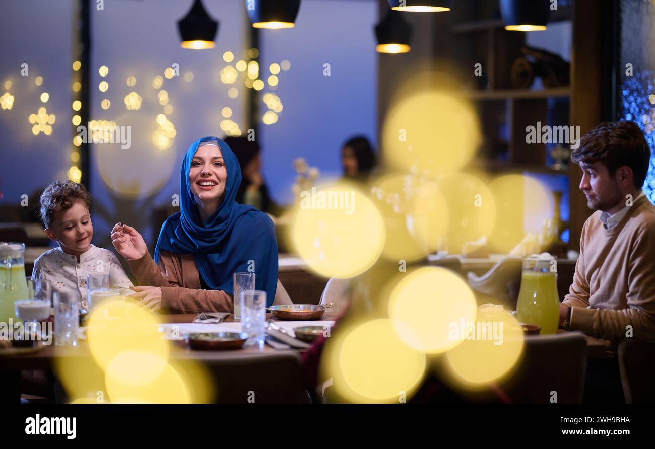 In a modern restaurant, an Islamic couple and their children joyfully ...