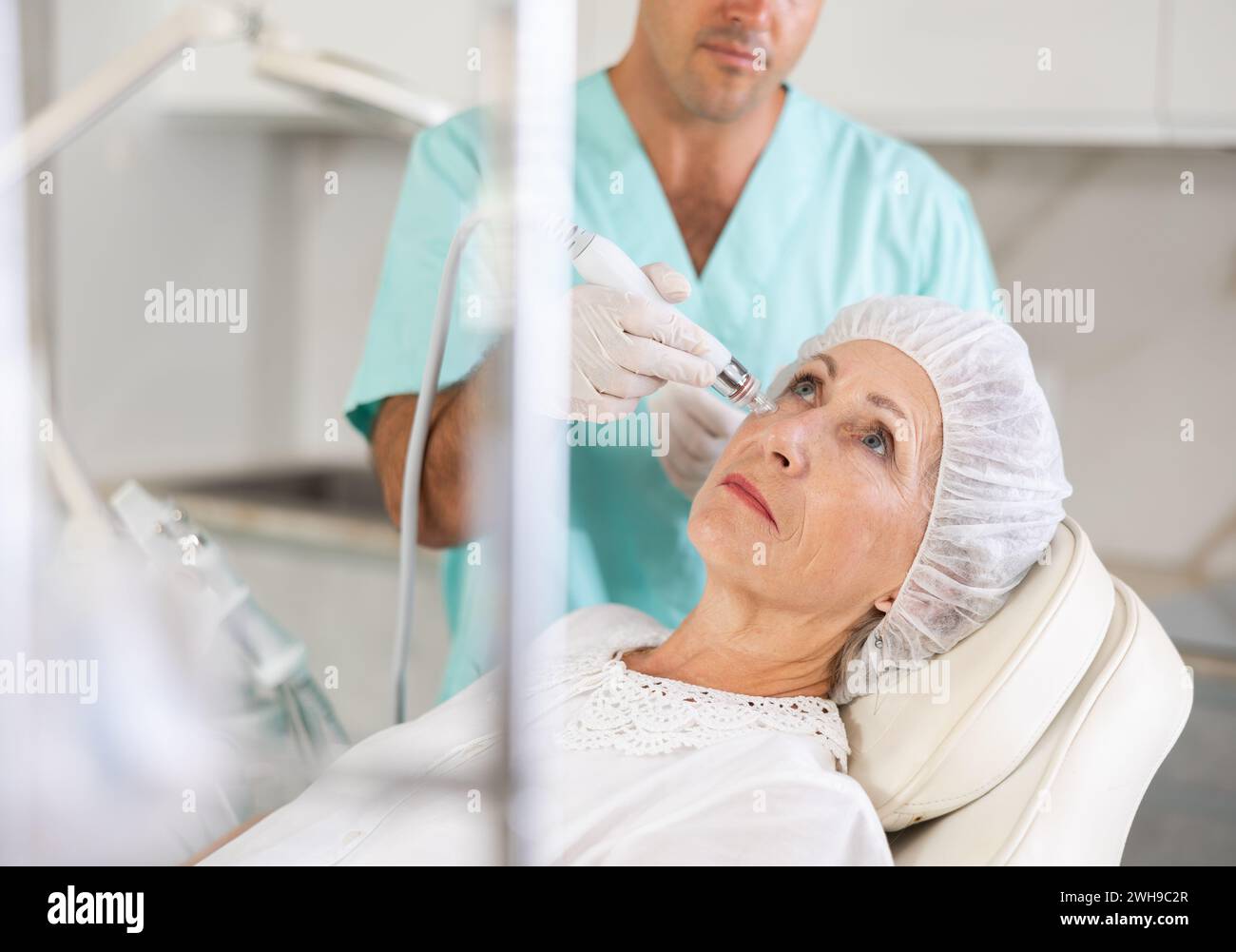 Mature woman getting facial deep hydration procedure from experienced ...
