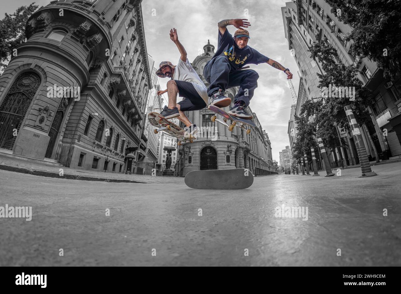 Two friend skaters jumping over a skateboard in downtown Santiago on a ...