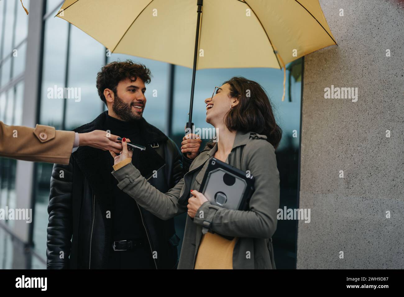 Two smiling friends enjoying a rainy day in the city, sharing a yellow ...