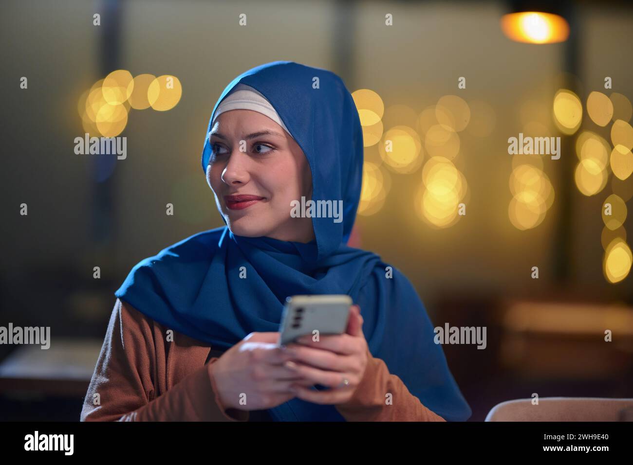 A beautiful European Muslim woman, adorned with a hijab, utilizes her ...