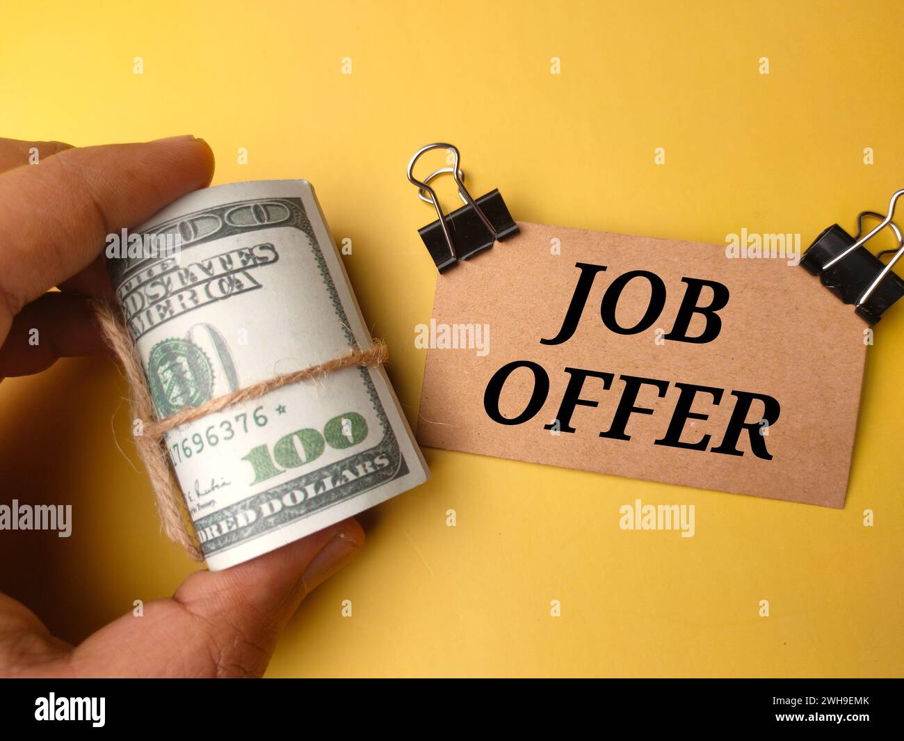 Top view brown card and banknotes with text JOB OFFER on a yellow ...