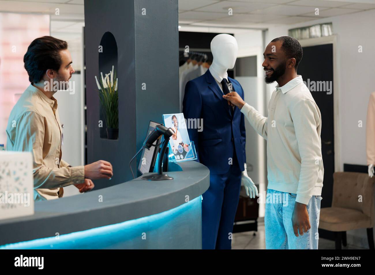 Clothing store customer talking with cashier and asking about jacket ...