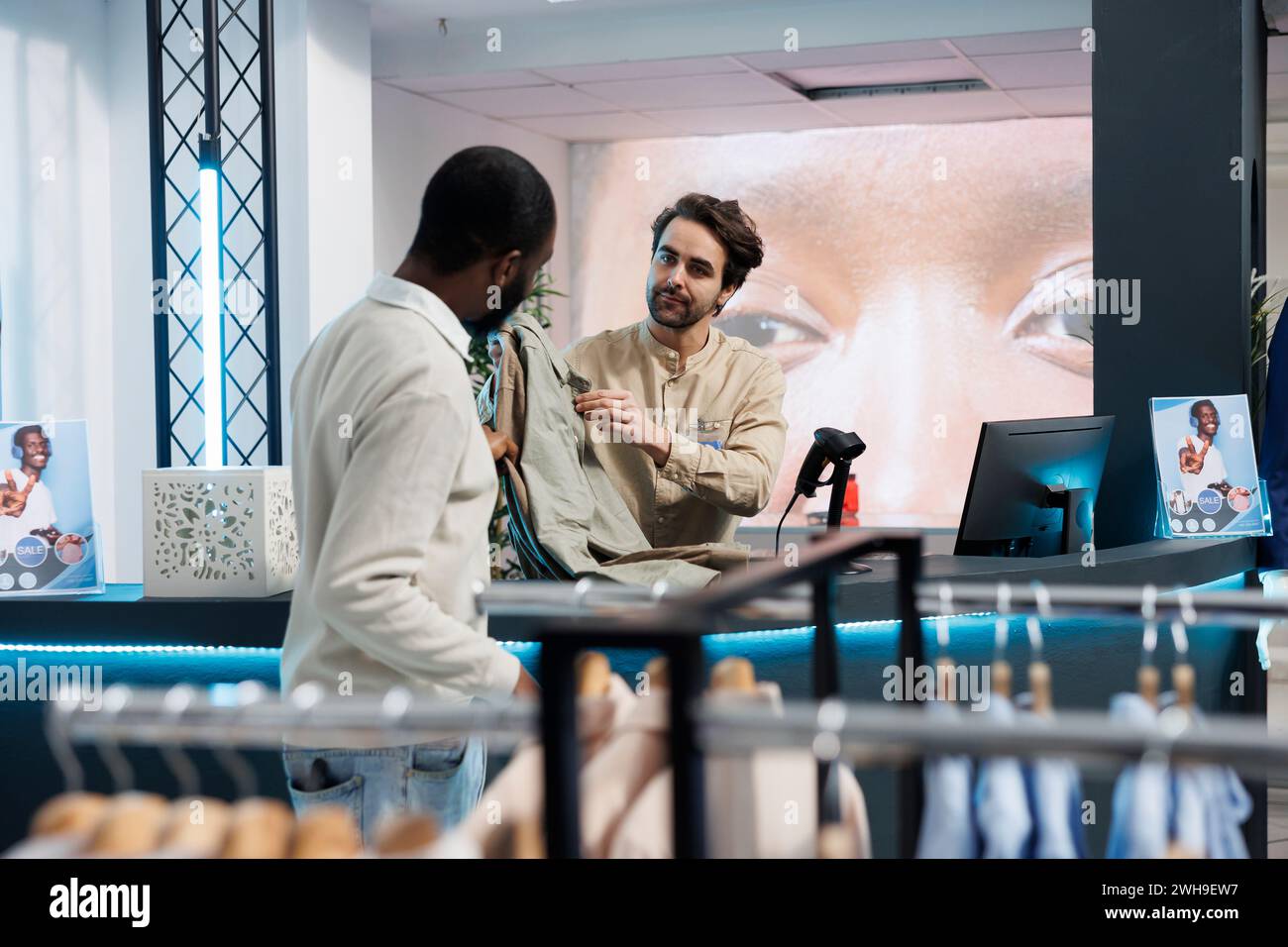 Clothing store cashier talking with customer and taking clothes at ...