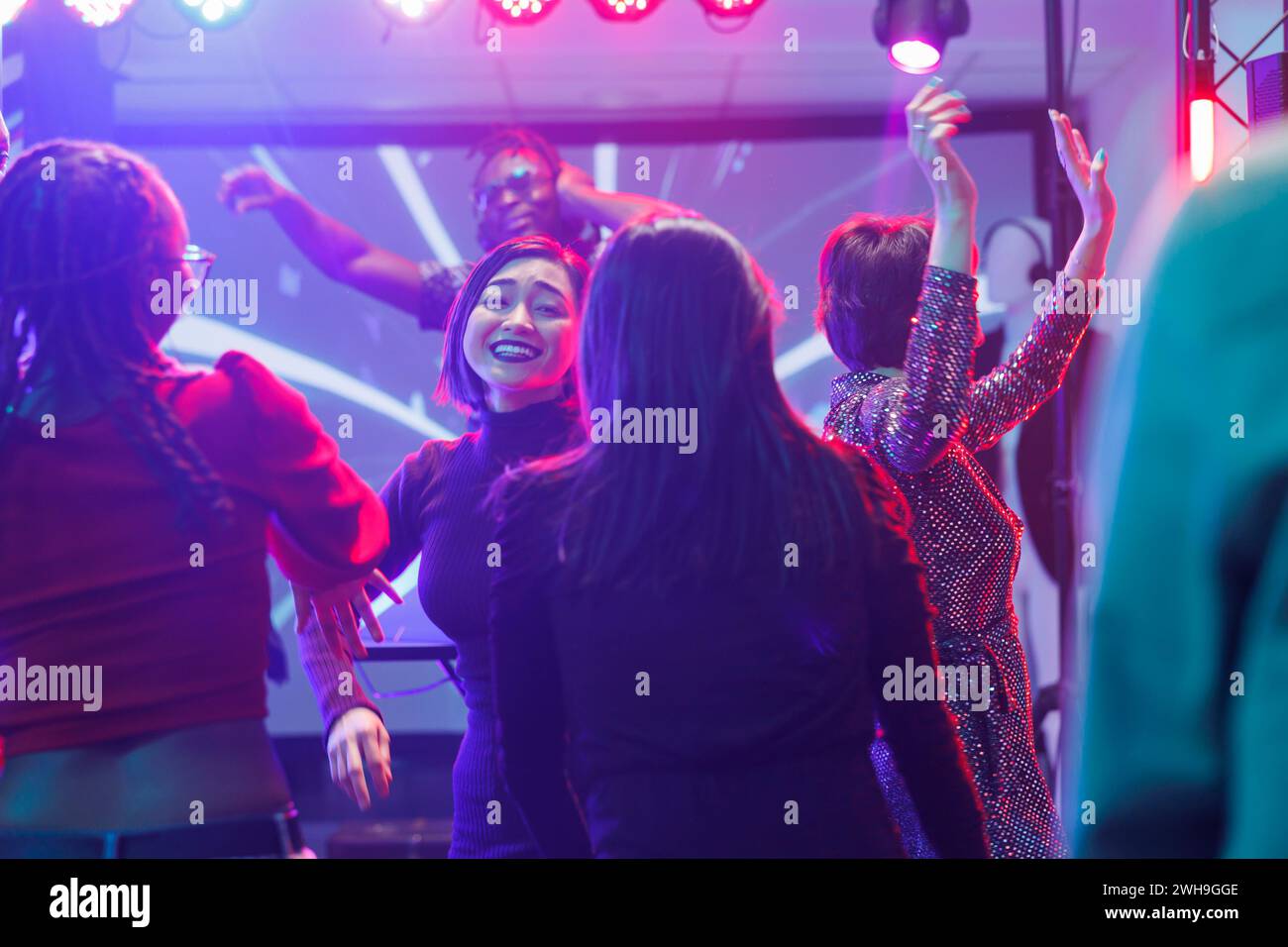 Happy diverse girlfriends partying and dancing at discotheque in ...