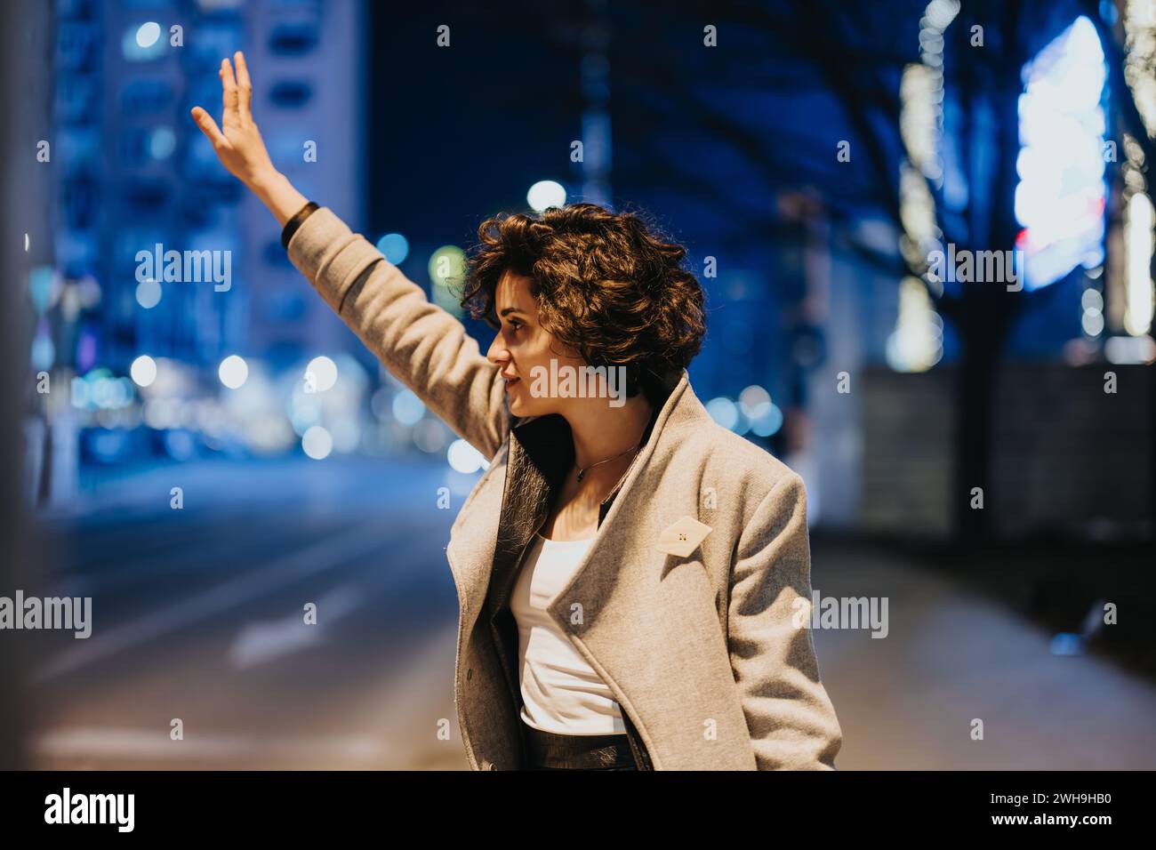 A young woman is captured hailing a cab on a bustling city street at ...