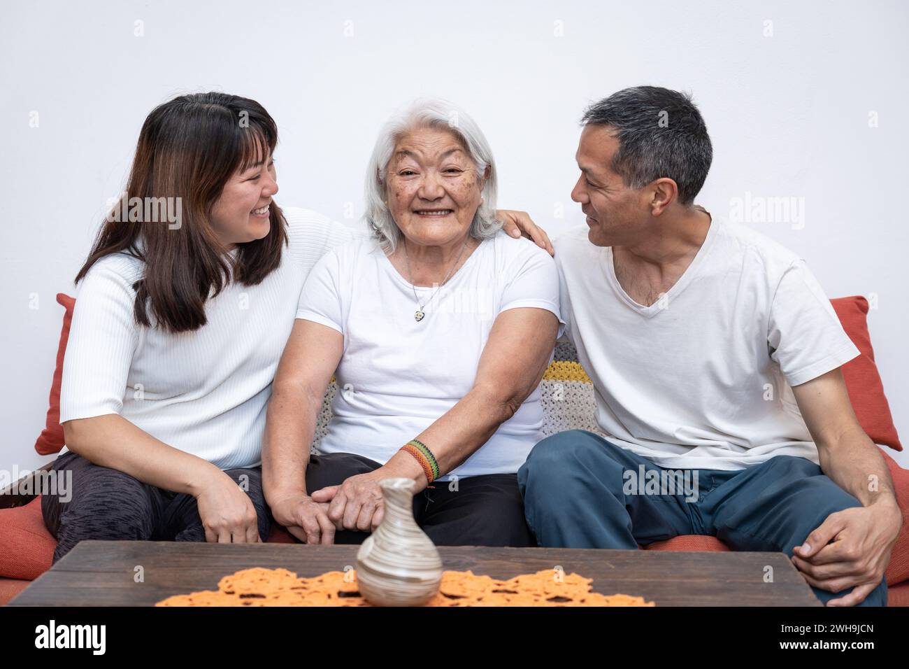 Adult children warmly embrace their elderly mother, who looks directly ...