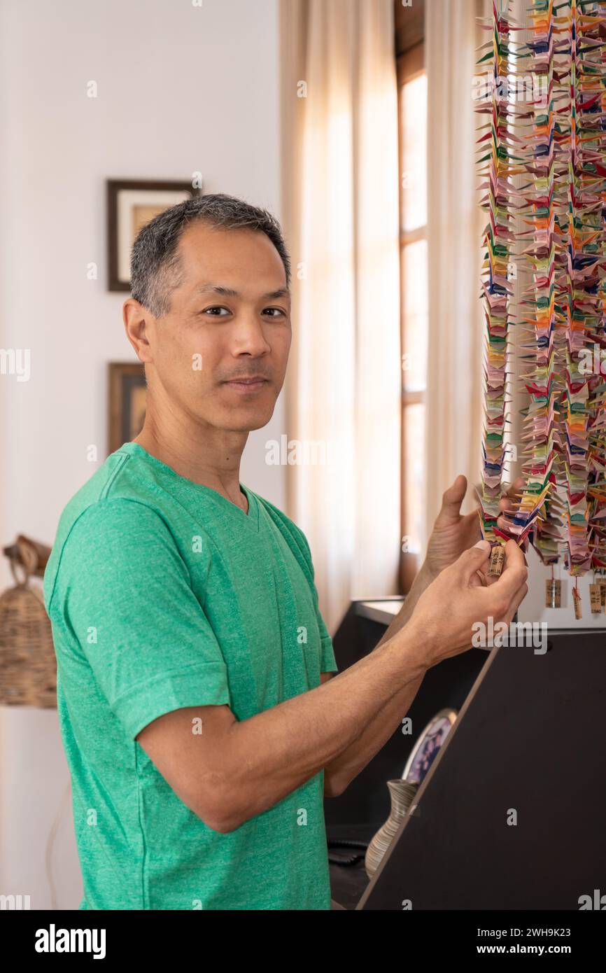 Japanese man holding a paper crane looking at camera. Memories in the ...