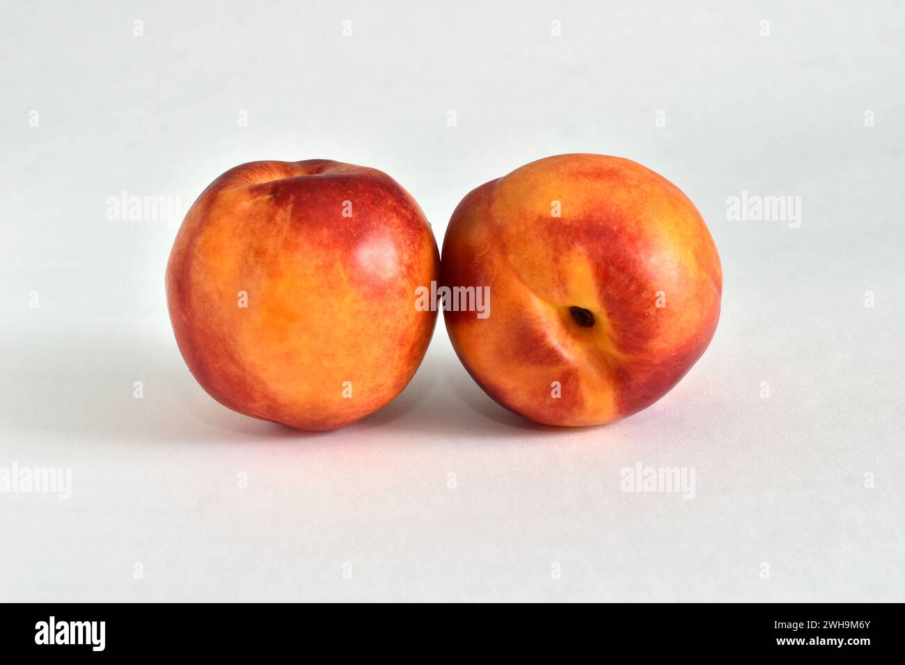 Two juicy, tasty, vitamin-rich nectarine fruits lie on a white ...