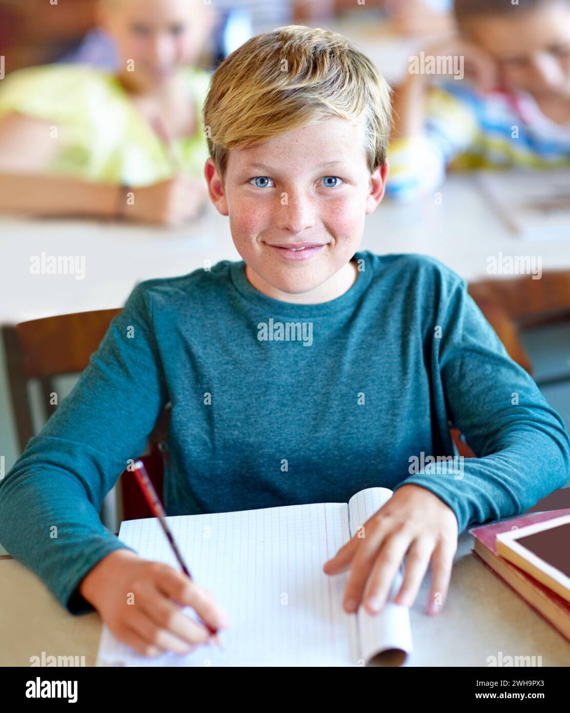 Student, portrait and boy writing notes for learning in classroom, book ...