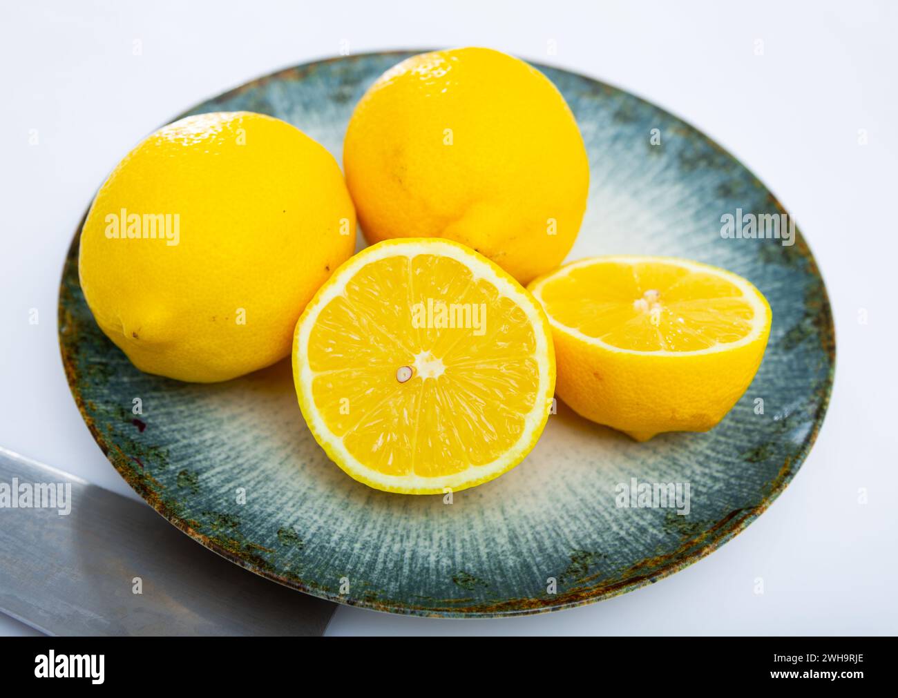 Whole lemons and pieces of fruit cut in half on dark blue plate Stock ...