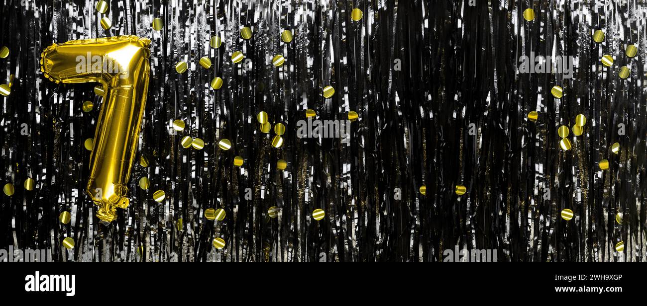Gold foil balloon number number 7 on a background of black tinsel ...