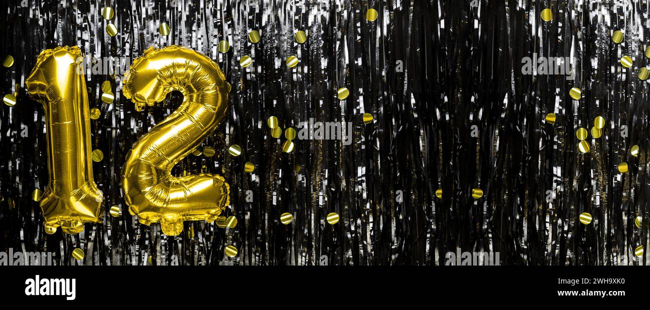 Gold foil balloon number number 12 on a background of black tinsel ...