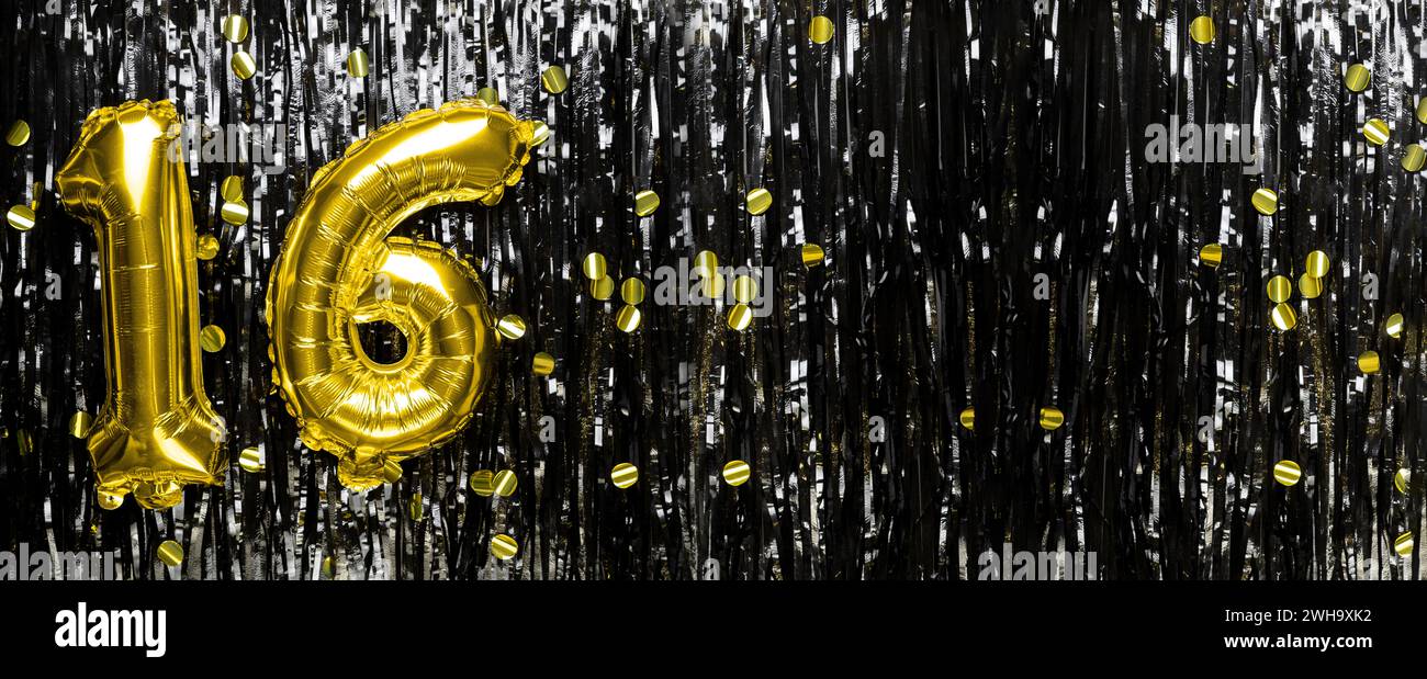 Gold foil balloon number number 16 on a background of black tinsel ...