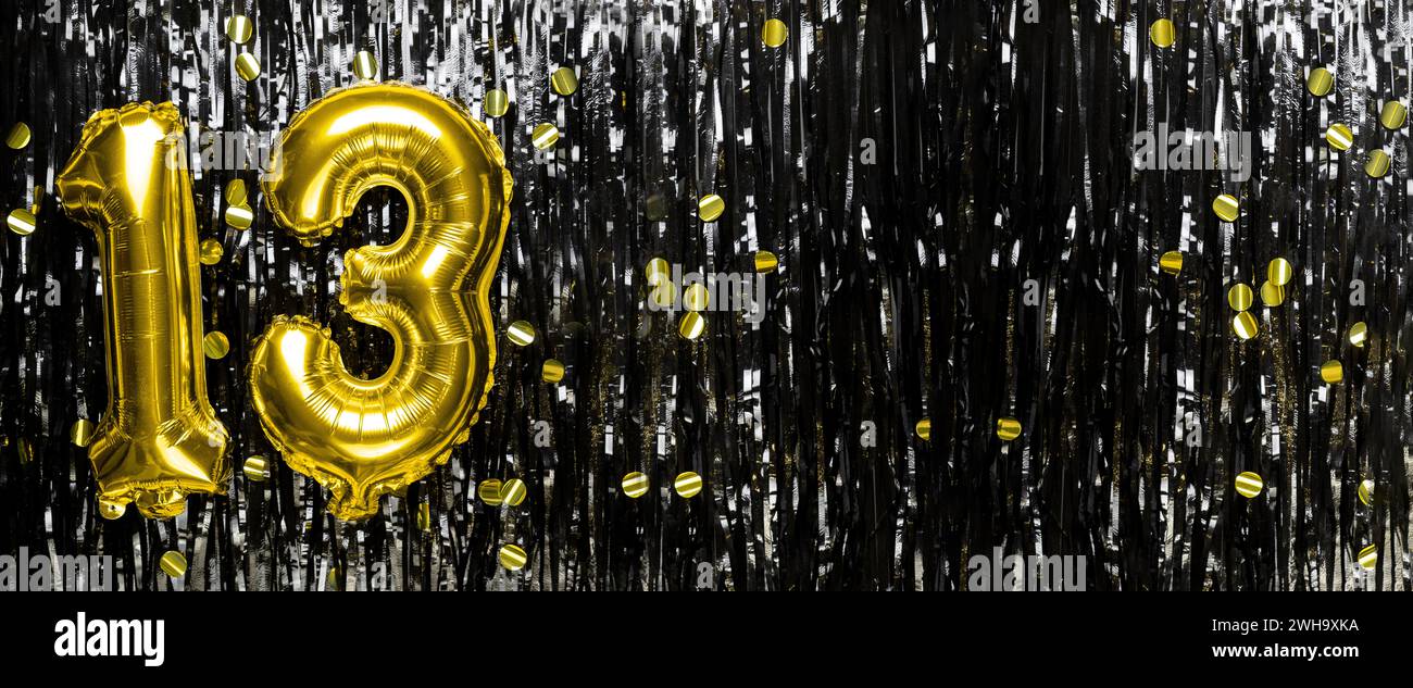Gold foil balloon number number 13 on a background of black tinsel ...