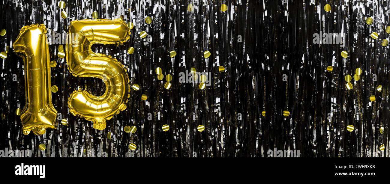 Gold foil balloon number number 15 on a background of black tinsel ...