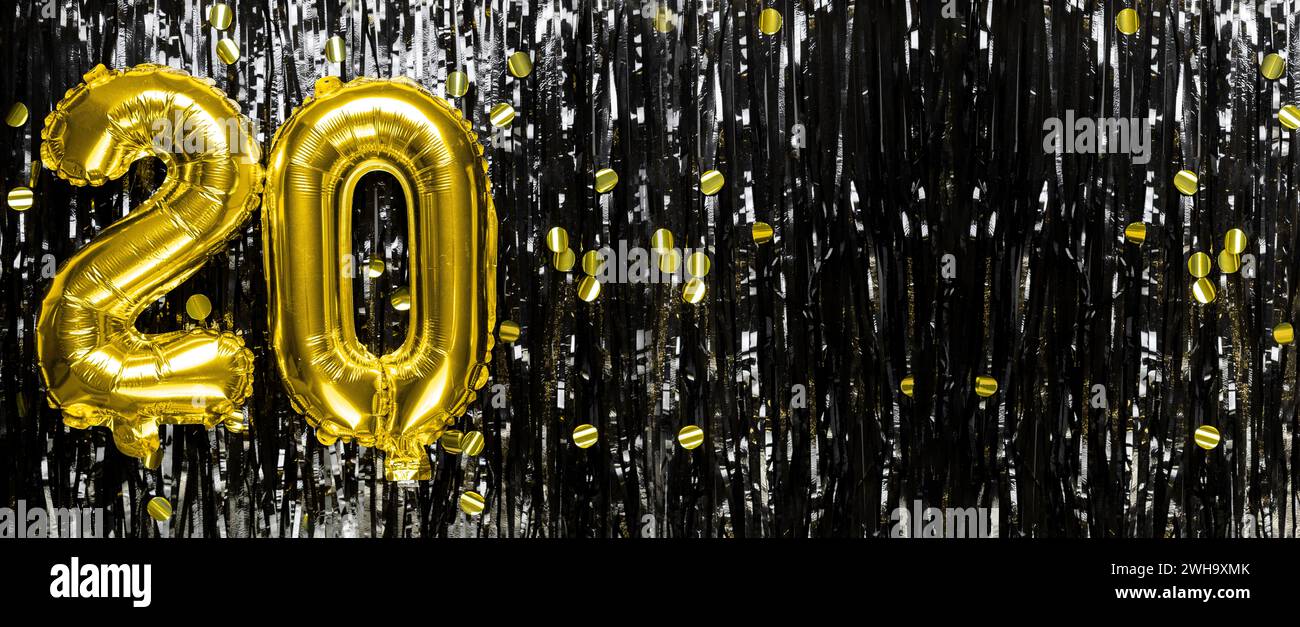 Gold foil balloon number number 20 on a background of black tinsel ...
