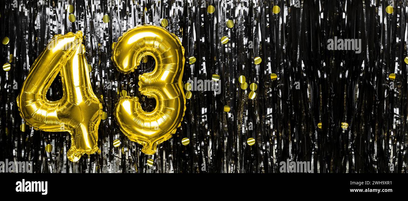 Gold foil balloon number number 43 on a background of black tinsel ...