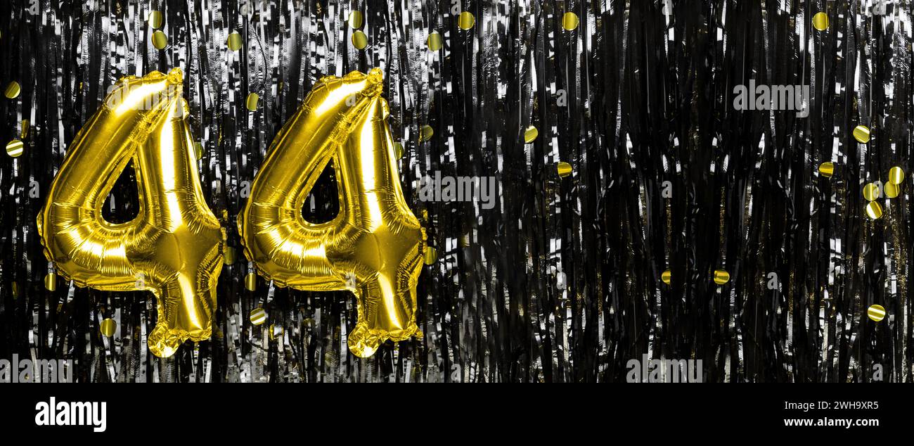 Gold foil balloon number number 44 on a background of black tinsel ...