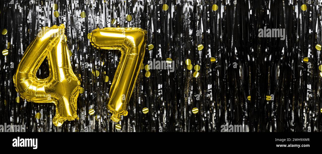 Gold foil balloon number number 47 on a background of black tinsel ...