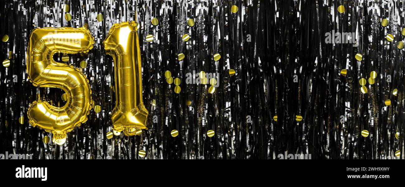 Gold foil balloon number number 51 on a background of black tinsel ...