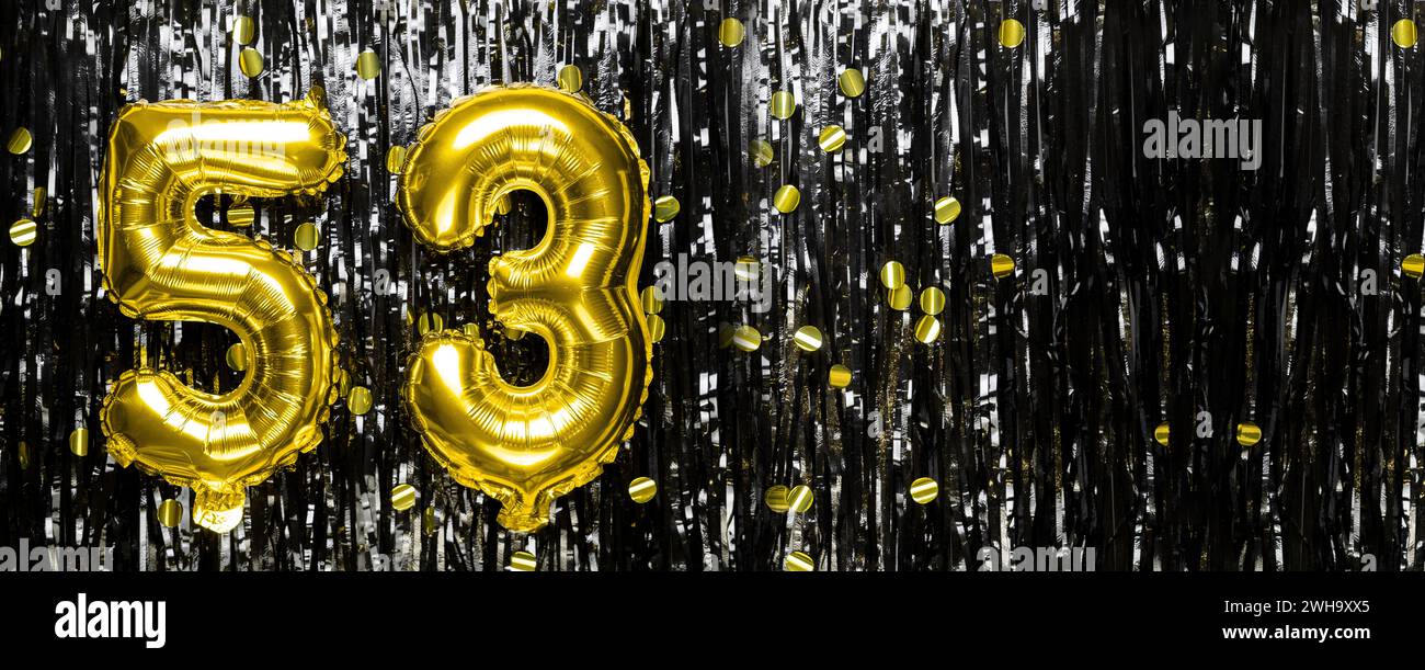 Gold foil balloon number number 53 on a background of black tinsel ...