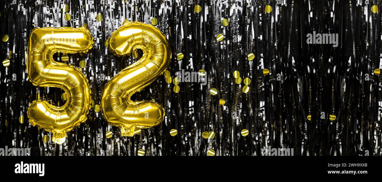 Gold foil balloon number number 52 on a background of black tinsel ...
