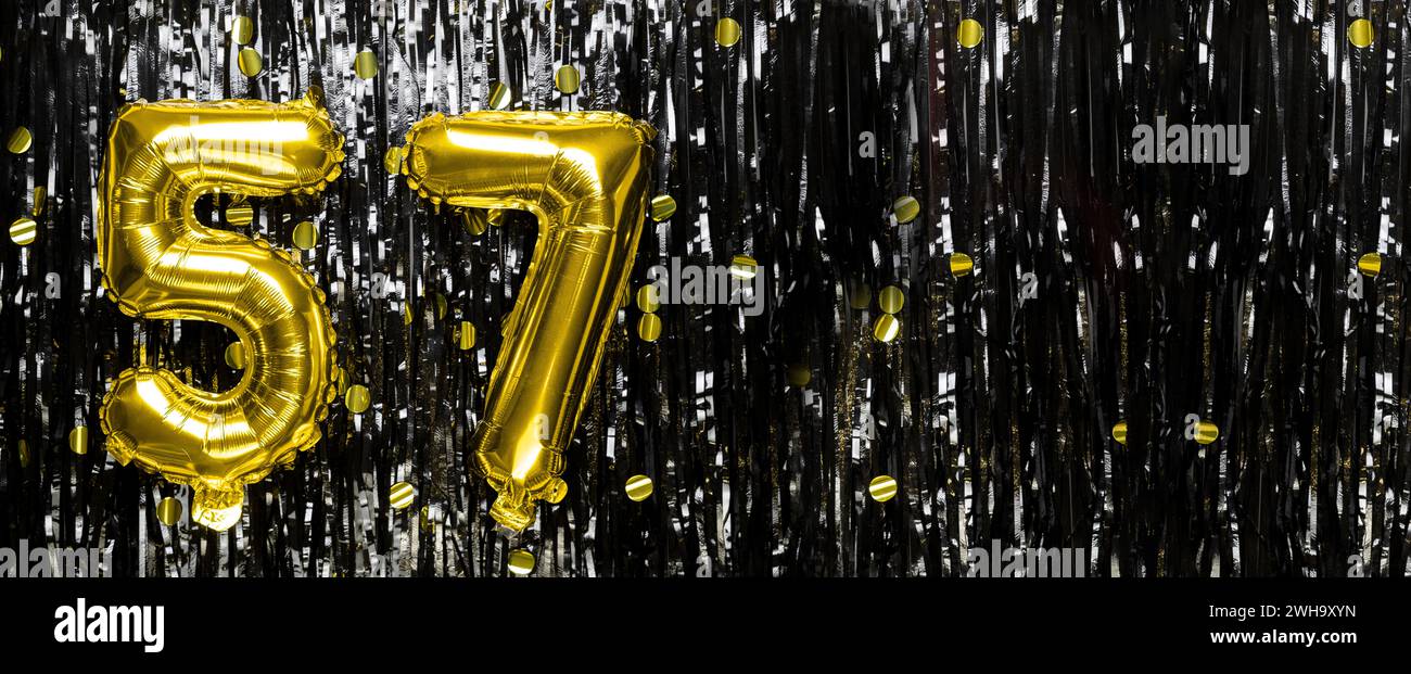 Gold foil balloon number number 57 on a background of black tinsel ...