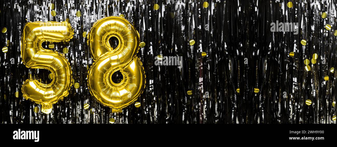 Gold foil balloon number number 58 on a background of black tinsel ...