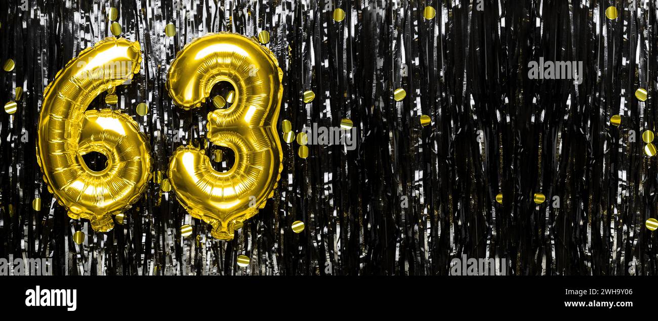 Gold foil balloon number number 63 on a background of black tinsel ...