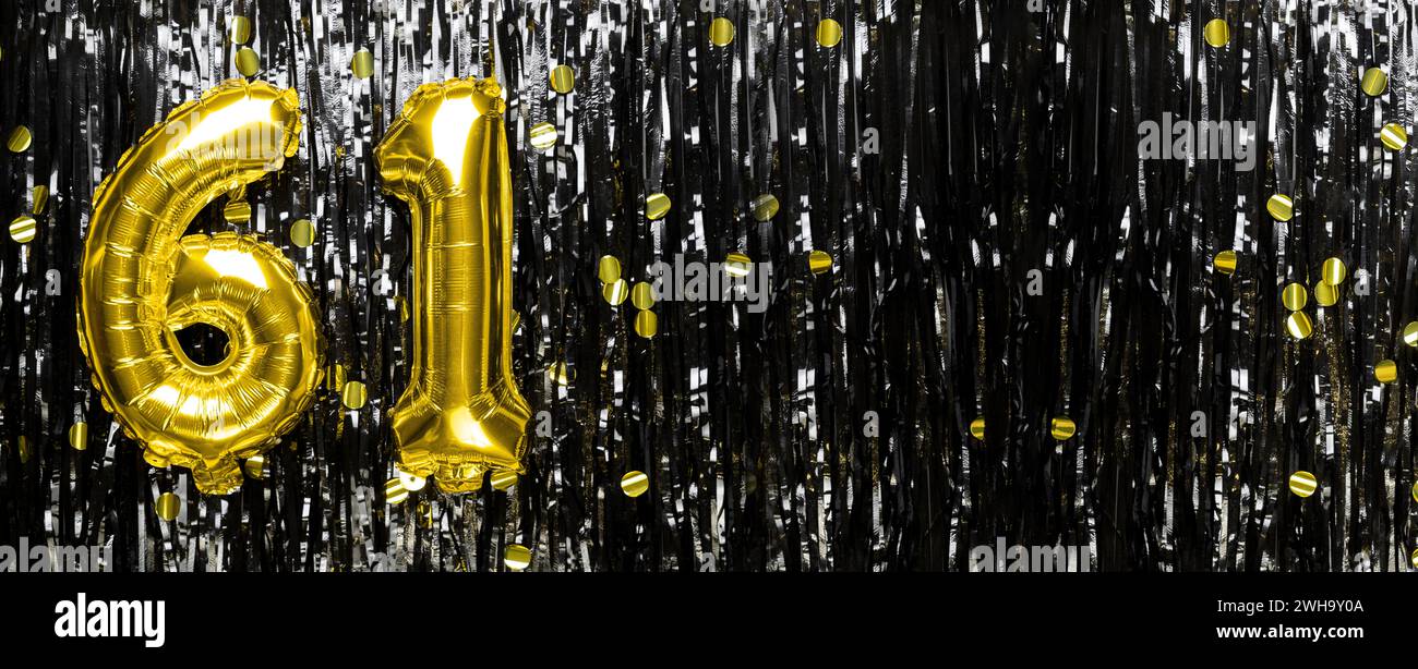 Gold foil balloon number number 61 on a background of black tinsel ...