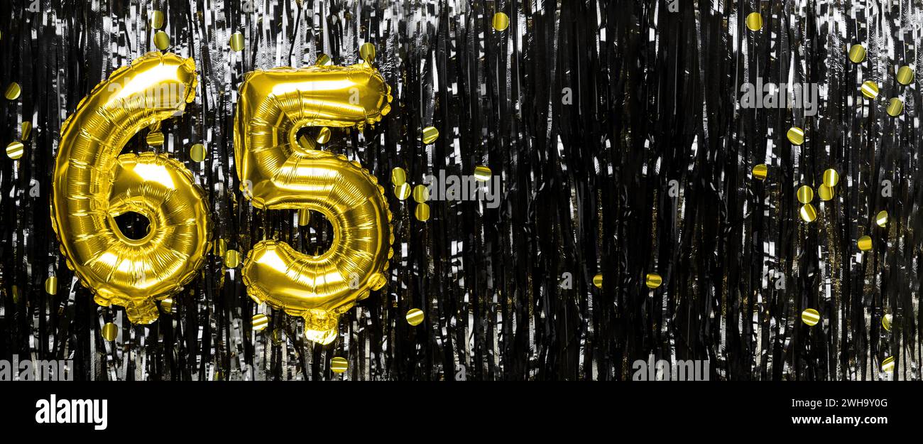Gold foil balloon number number 65 on a background of black tinsel ...