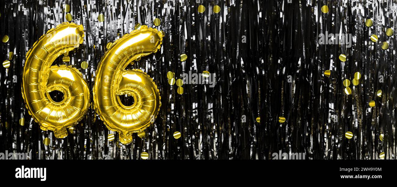 Gold foil balloon number number 66 on a background of black tinsel ...