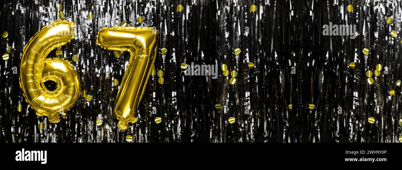 Gold foil balloon number number 67 on a background of black tinsel ...