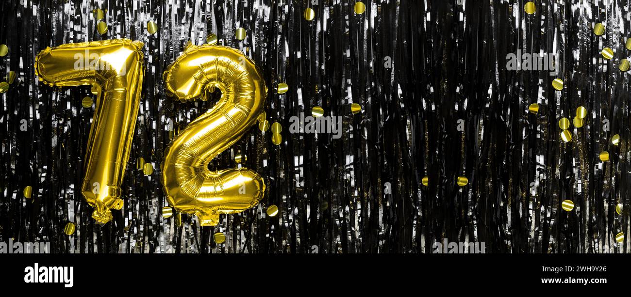 Gold foil balloon number number 72 on a background of black tinsel ...