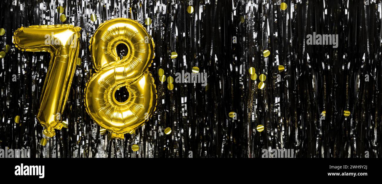 Gold foil balloon number number 78 on a background of black tinsel ...