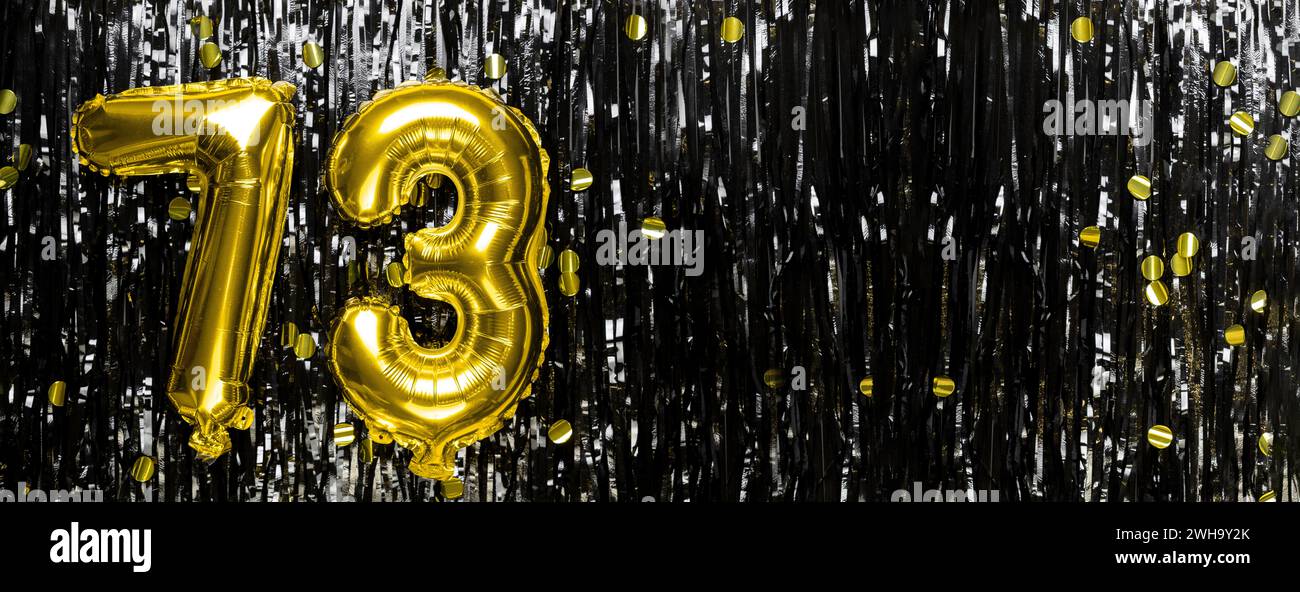 Gold foil balloon number number 73 on a background of black tinsel ...