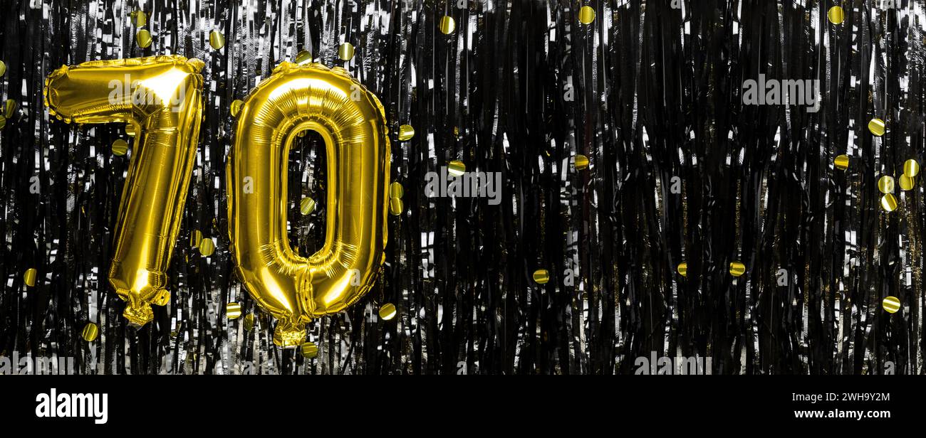 Gold foil balloon number number 70 on a background of black tinsel ...