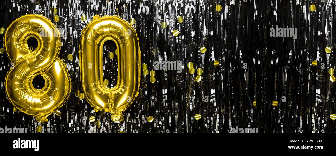 Gold foil balloon number number 80 on a background of black tinsel ...