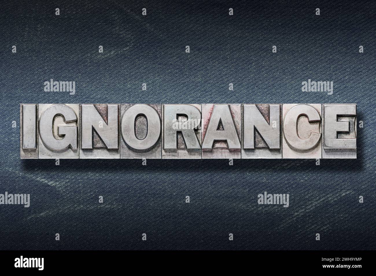 ignorance word made from metallic letterpress on dark jeans background ...