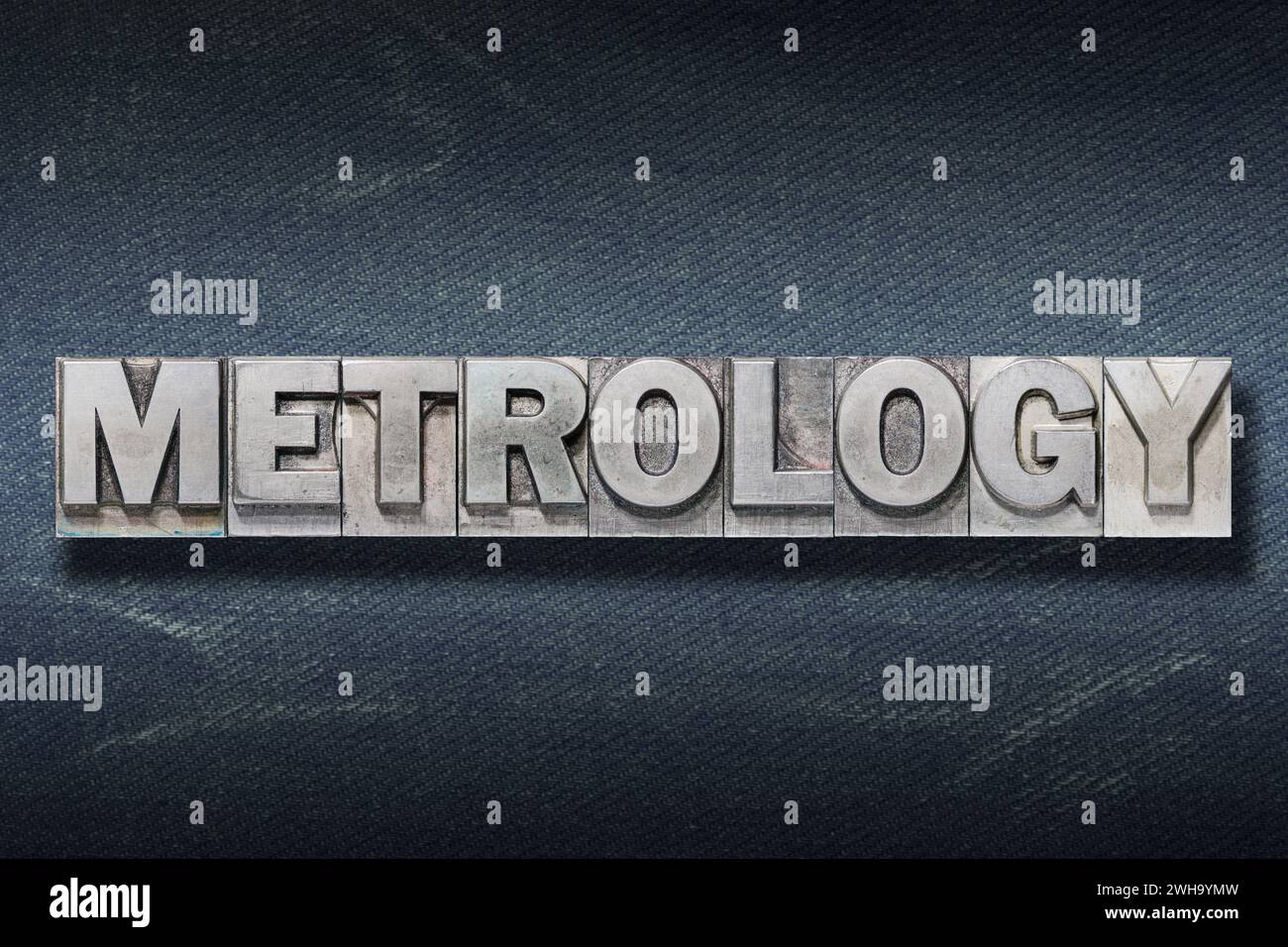 metrology word made from metallic letterpress on dark jeans background ...