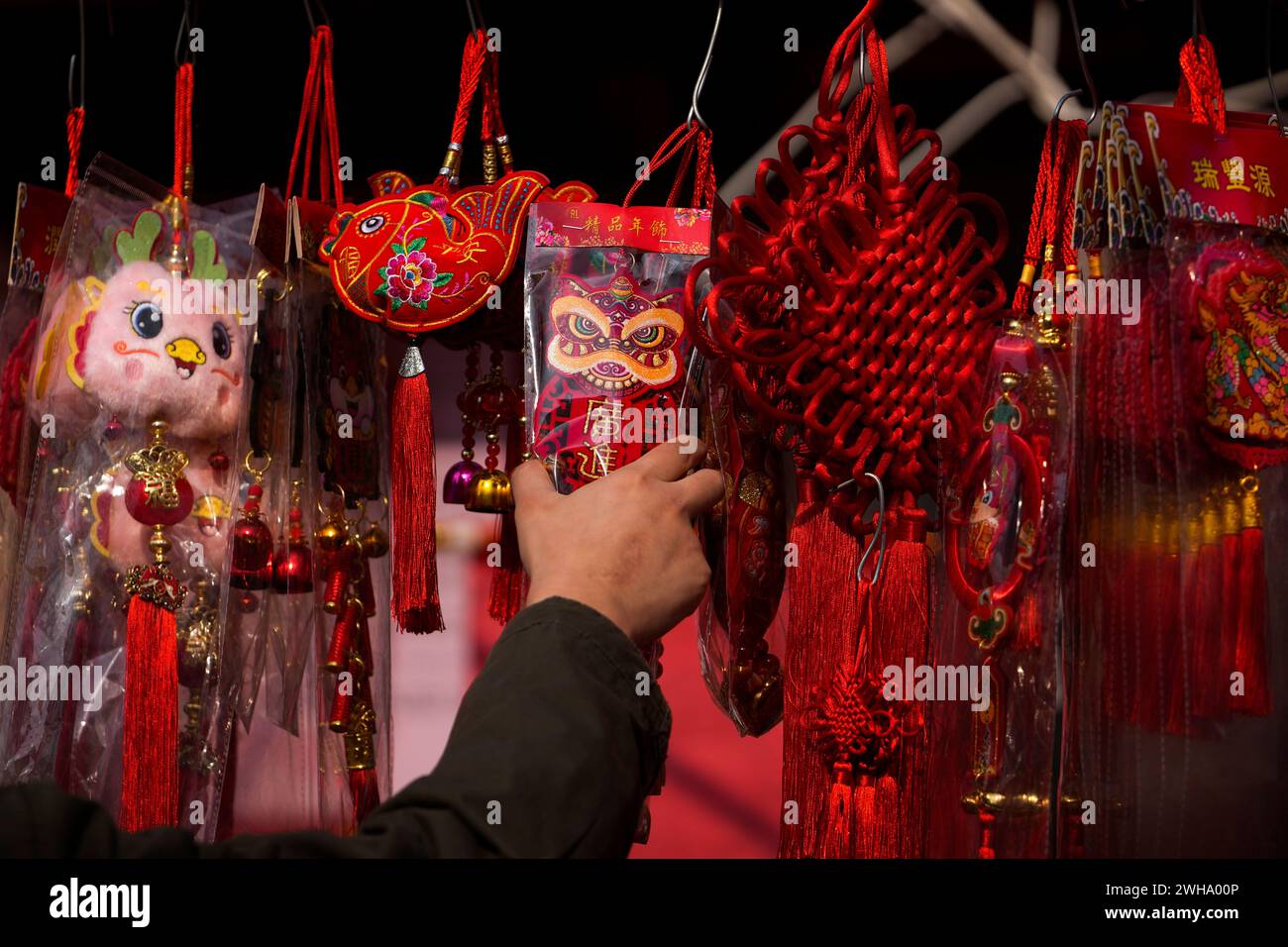 A man selects prosperity decorations on display for sale at a pavement ...