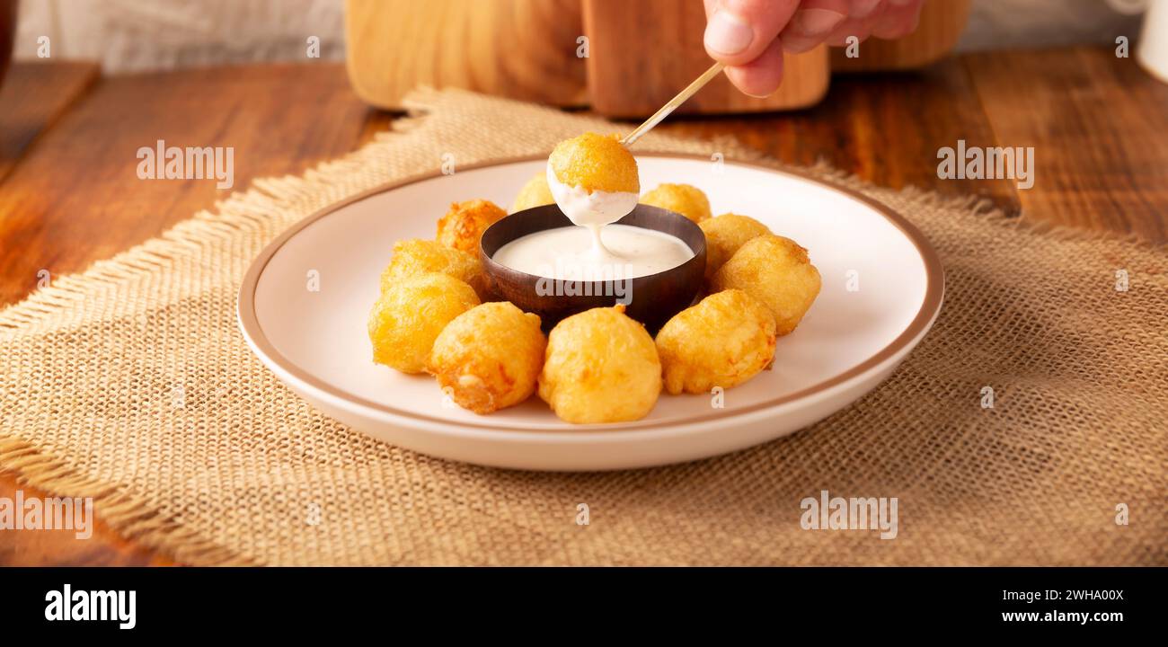 Human hand dipping a Fried breaded cheese bite, easy and delicious ...